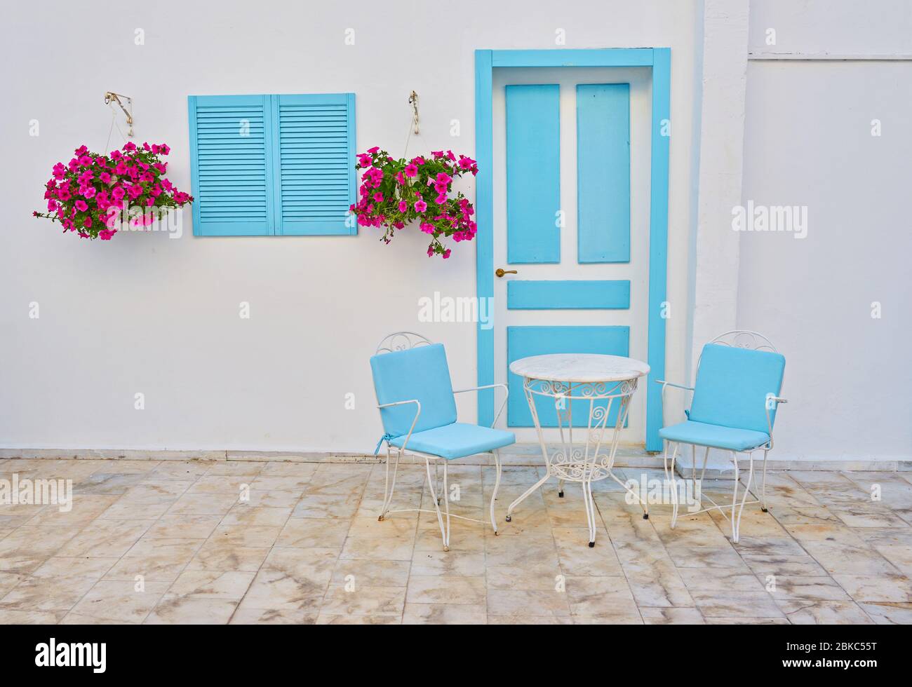 Classic view of a Greek blue window on a white wall with coffee table ...