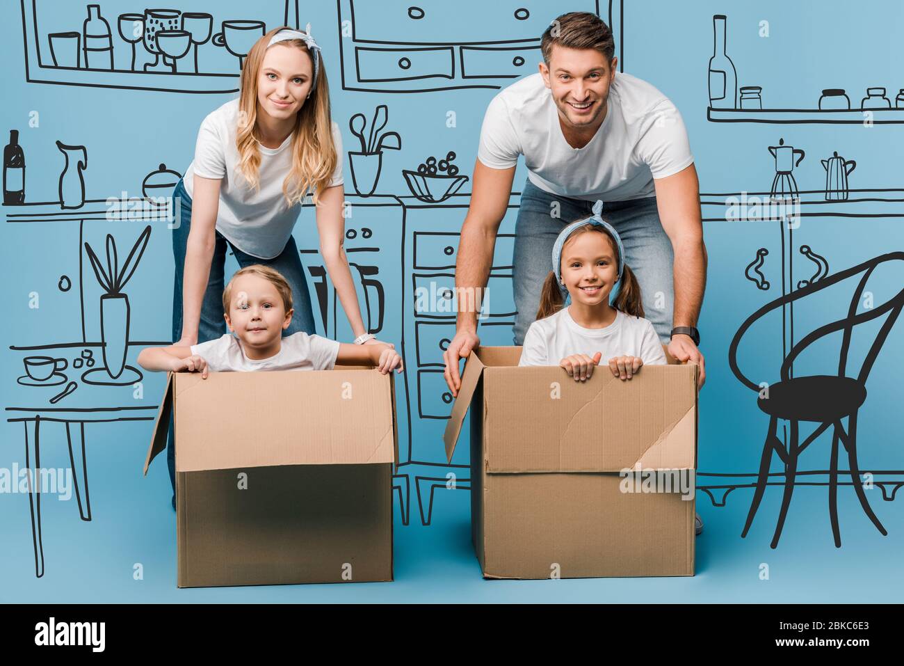 smiling parents with children in cardboard boxes for relocation on blue ...