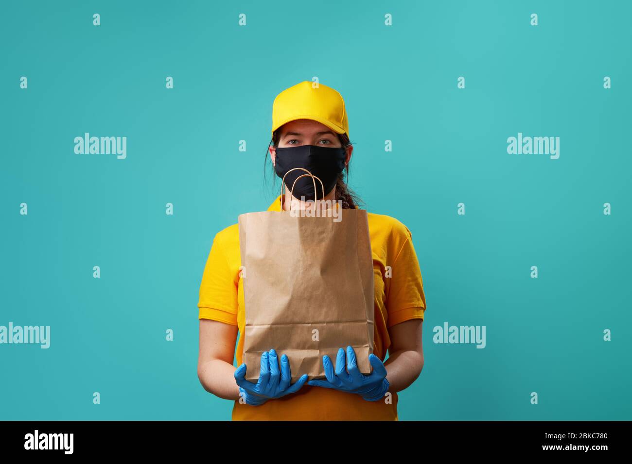 Courier with medical mask on his face holds bag in his hand. Concept of ...