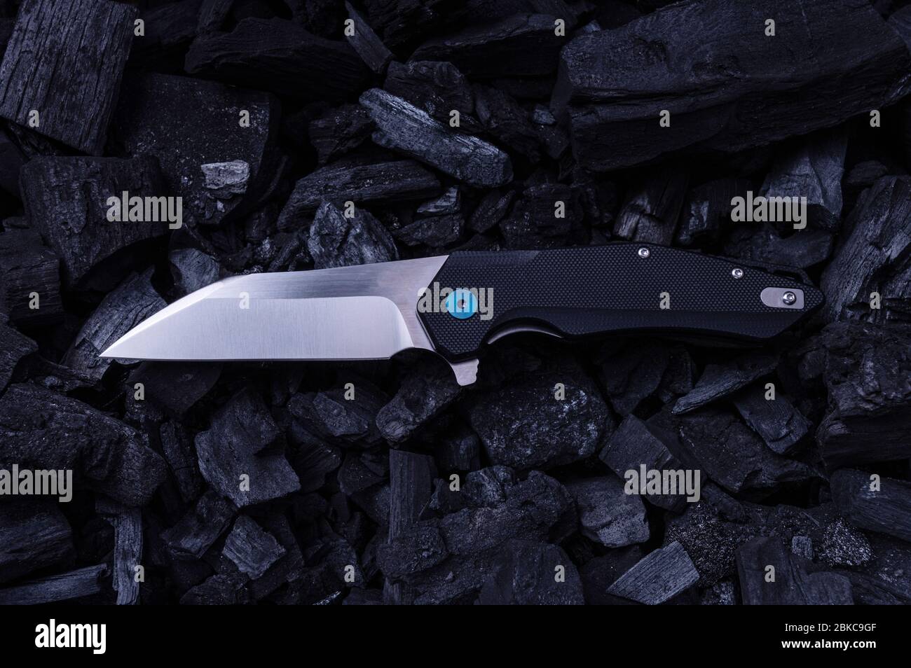 Pocket knife lying on cold coals. Top view of a knife and coal Stock ...