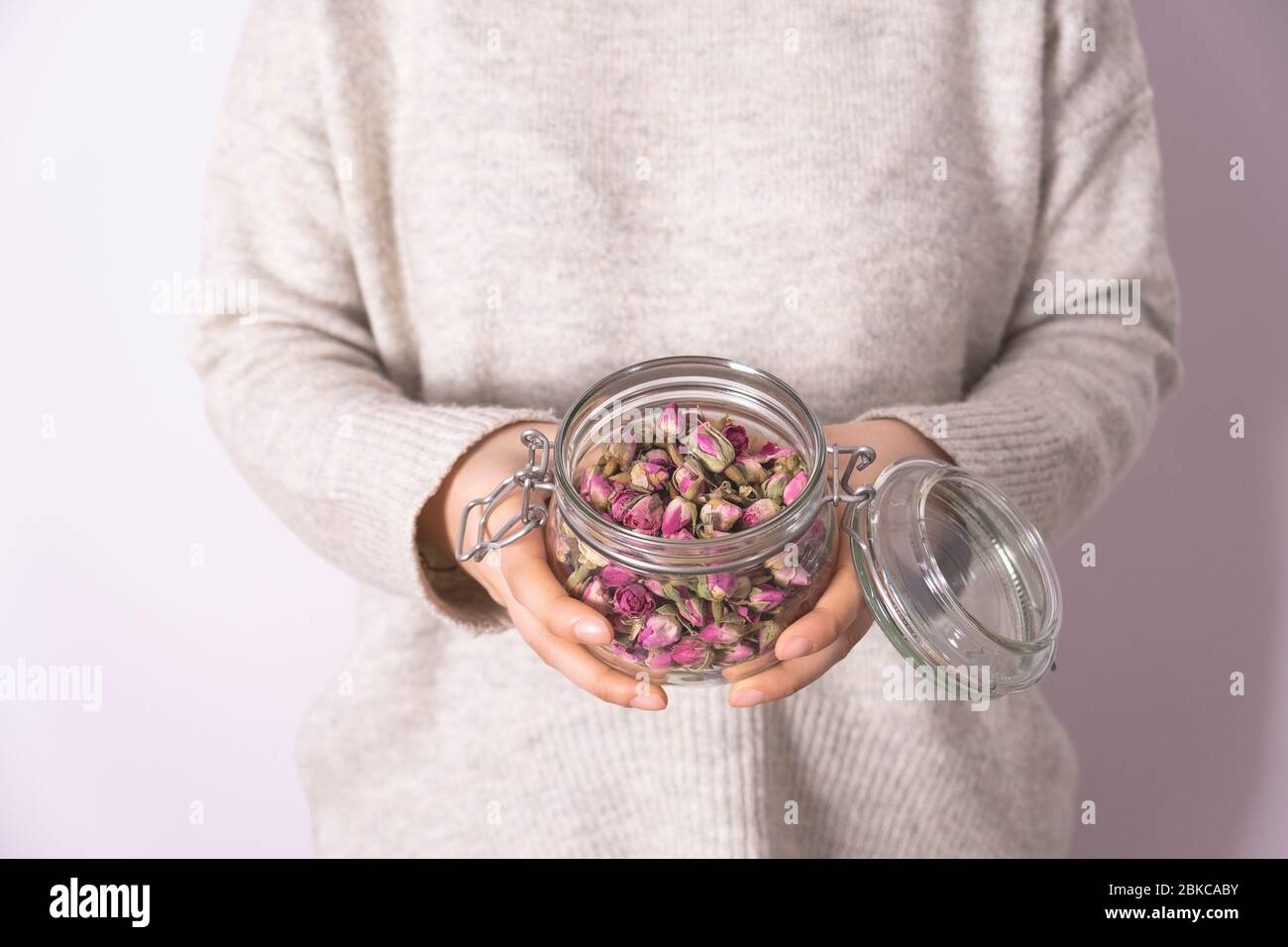 Dry rose buds for tea on jar in hand. Aromatic and healthy herbal tea ...