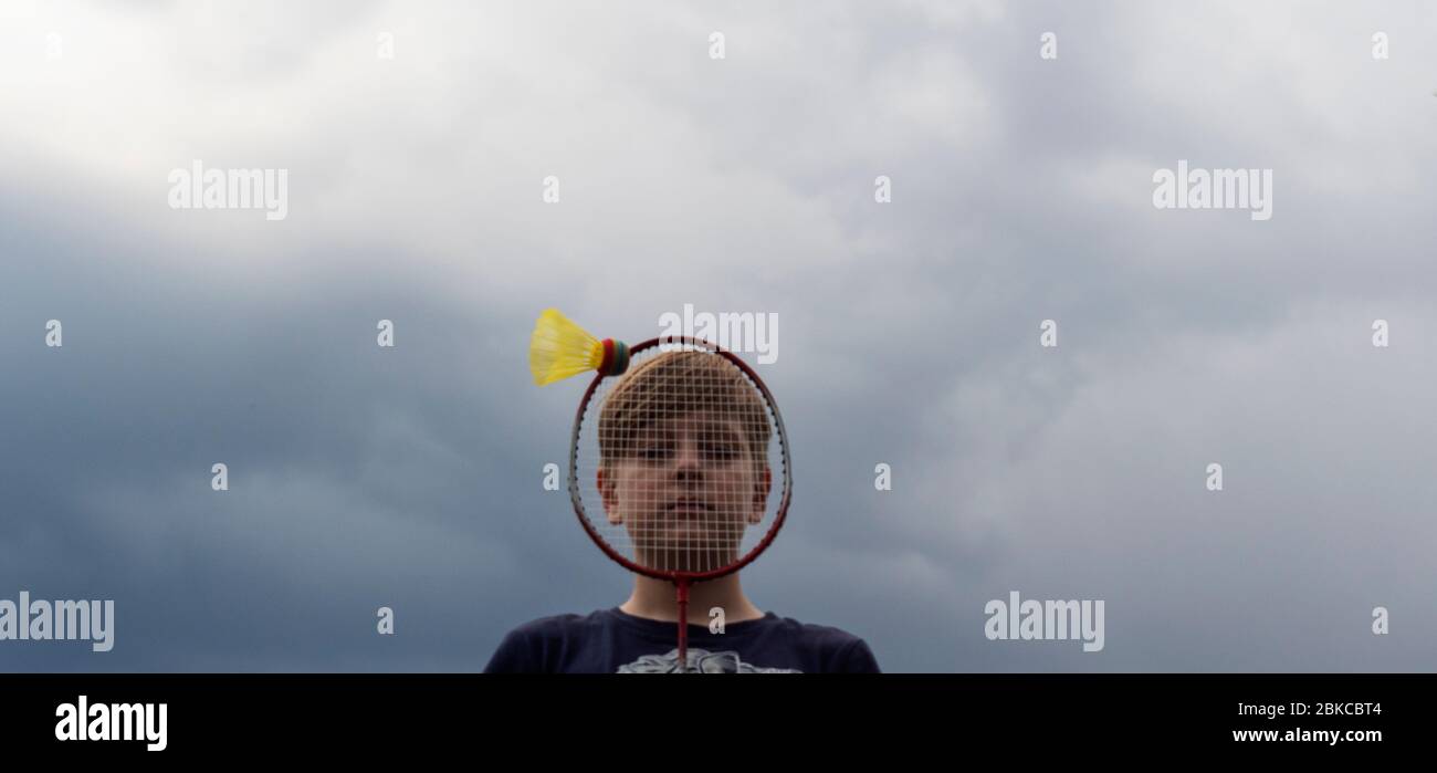 Caucasian boy play badminton on sky background. The boy covered his ...