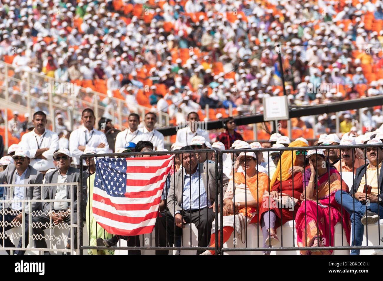 Audience members displaying a U.S. flag listen to President Donald J ...
