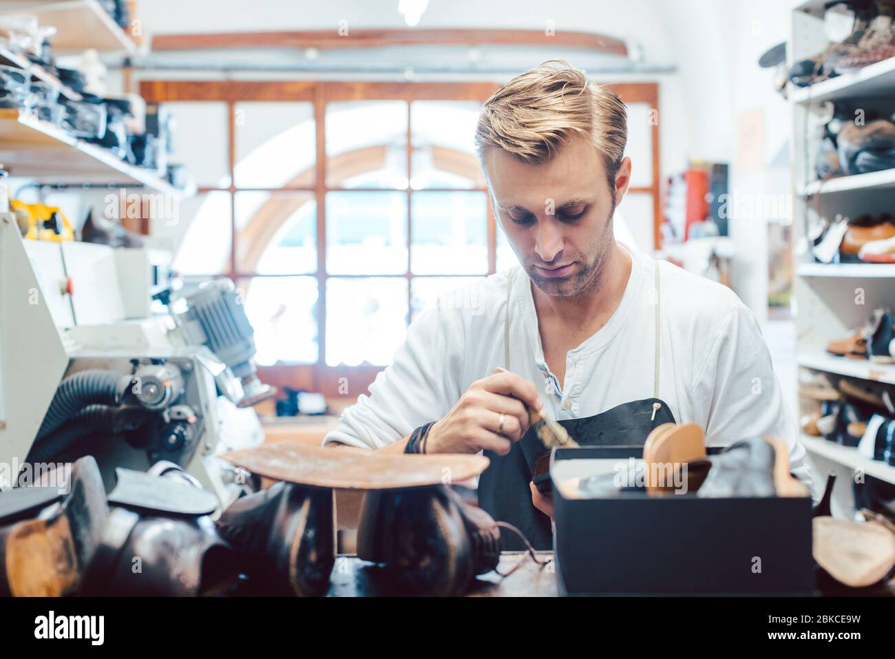 Shoemaker putting glue on sole of a shoe Stock Photo - Alamy