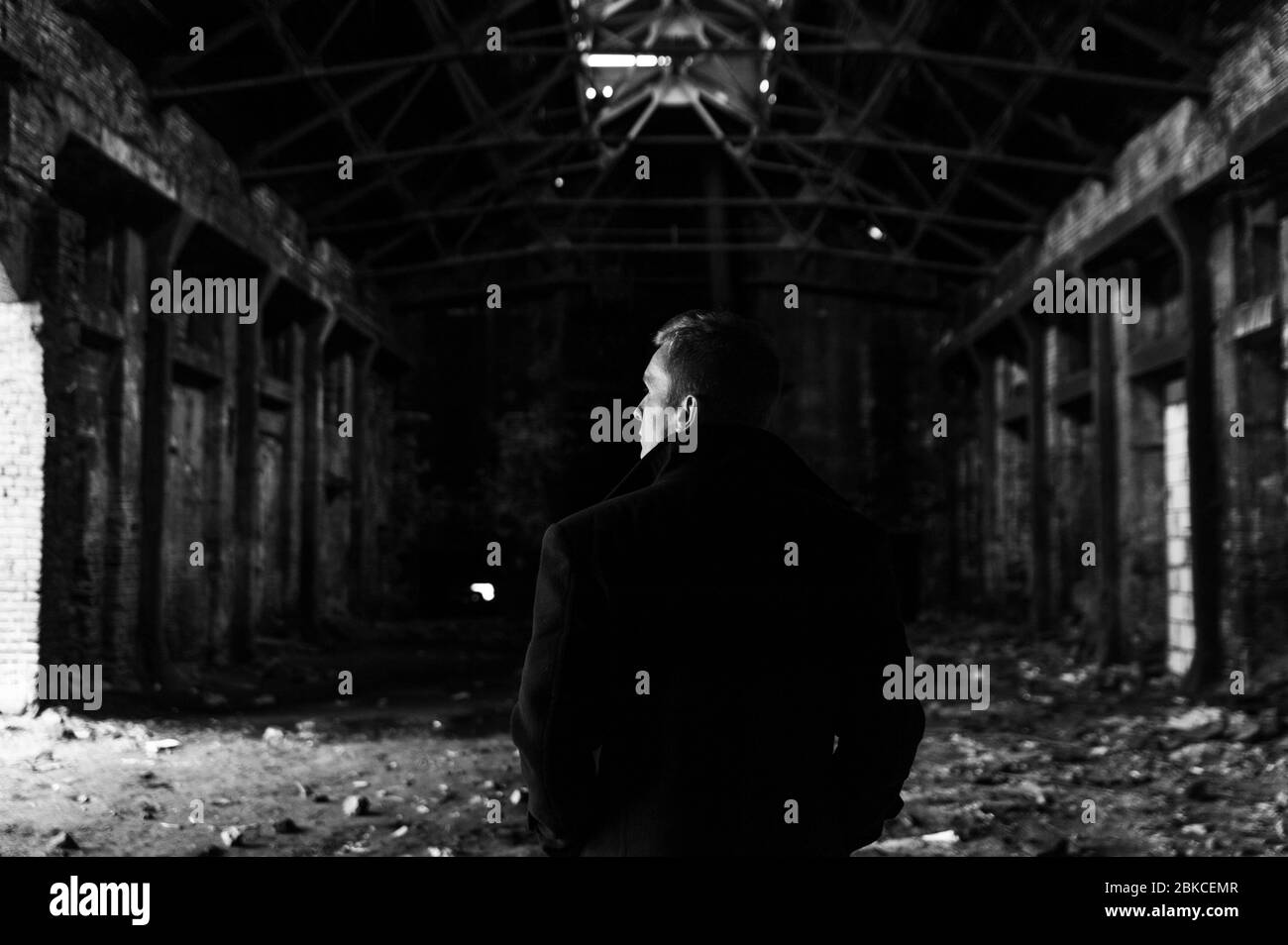 Man in the coat standing in the abandoned building photographed from ...