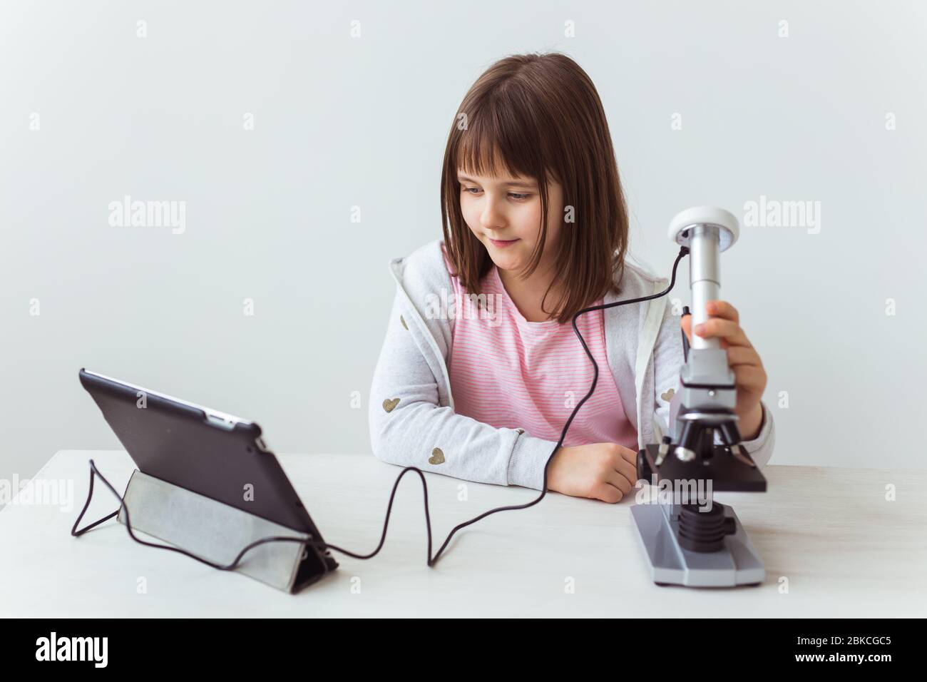 Portrait of cute little child doing homework with a digital microscope ...