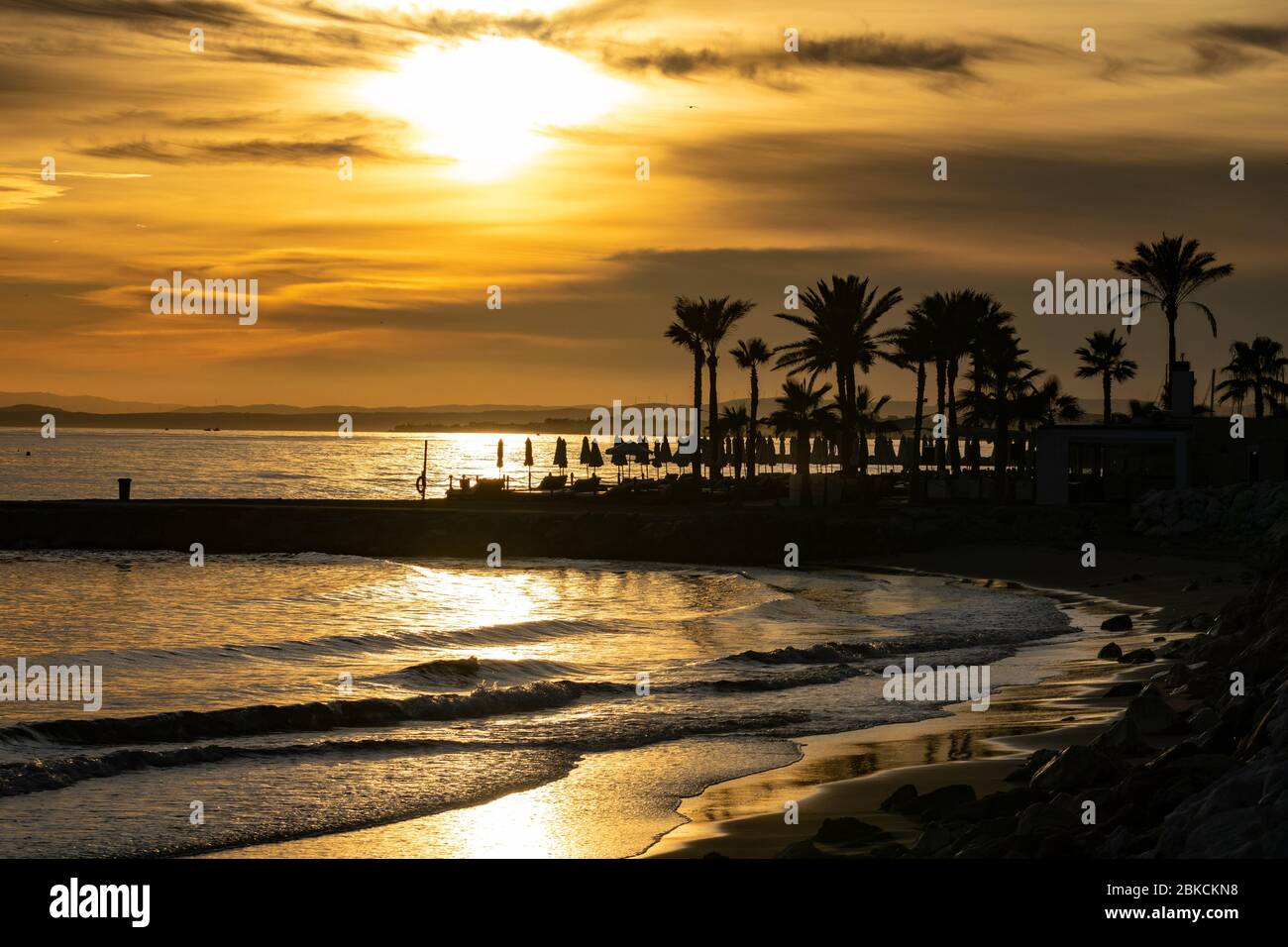 a golden beach scene of a sunset setting in Marbella, Spain Stock Photo ...