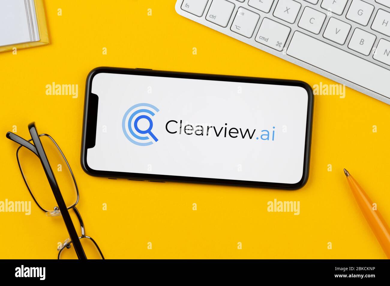 A smartphone showing the Clearview.ai logo rests on a yellow background ...
