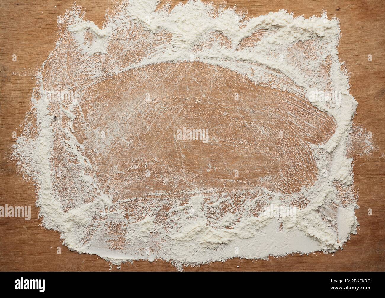 white wheat flour scattered on a brown wooden table, top view, kitchen ...