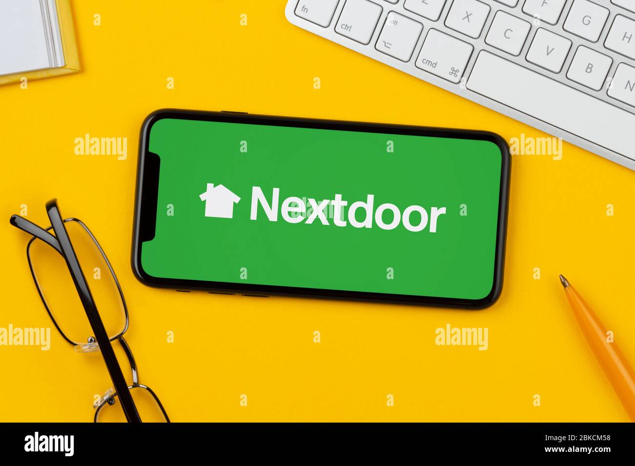 A smartphone showing the Nextdoor logo rests on a yellow background ...