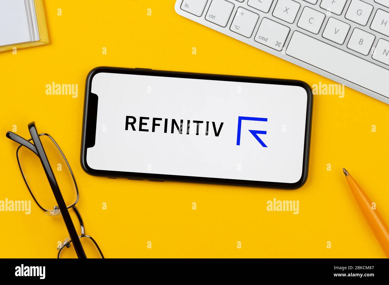 A smartphone showing the Refinitiv logo rests on a yellow background ...