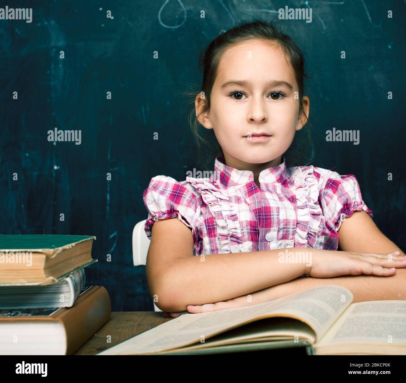 portrait of happy cute student with book in classroom near blackboard ...
