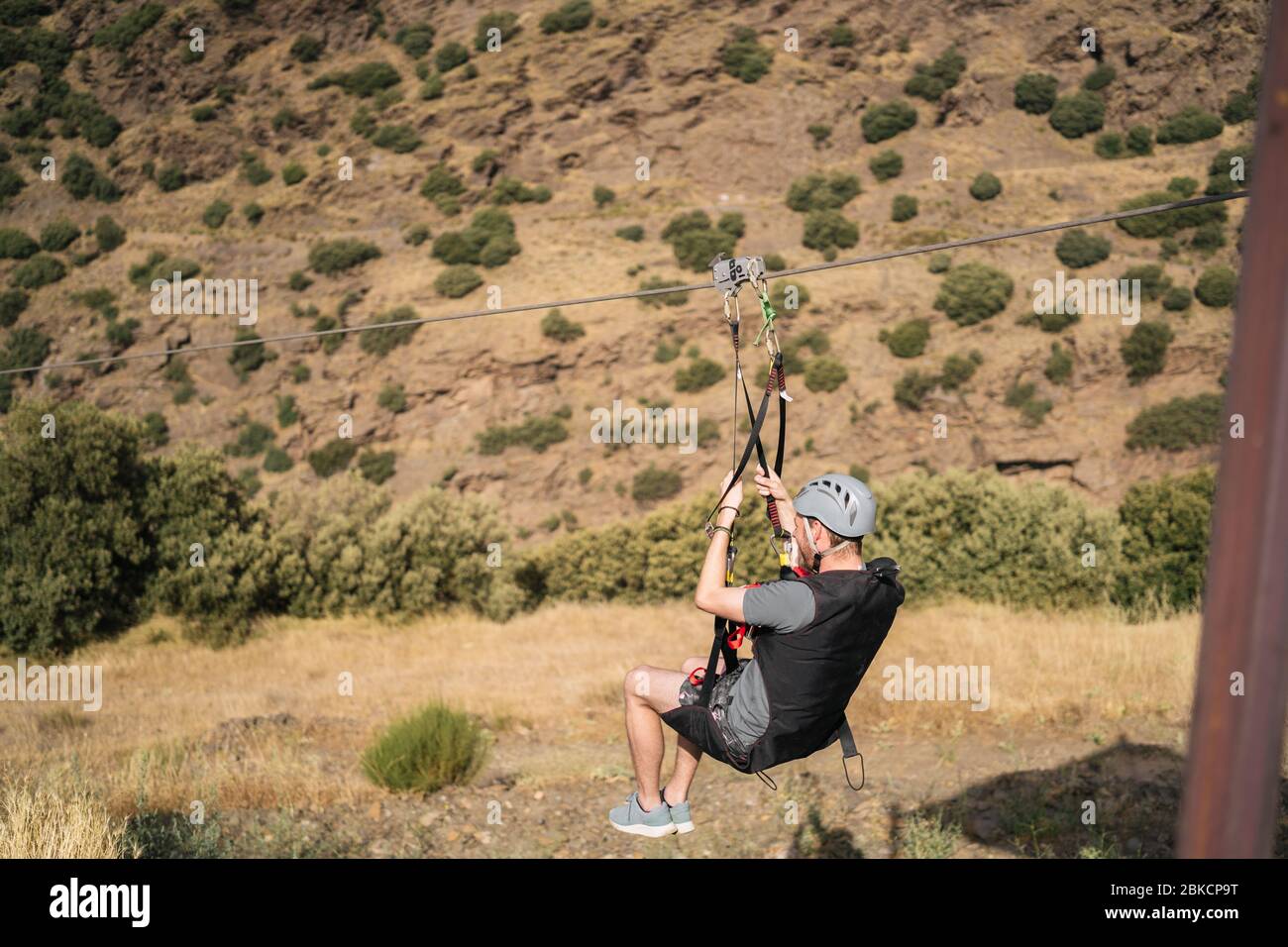 Zip line is an exciting adventure activity. Man hanging on a rope-way ...