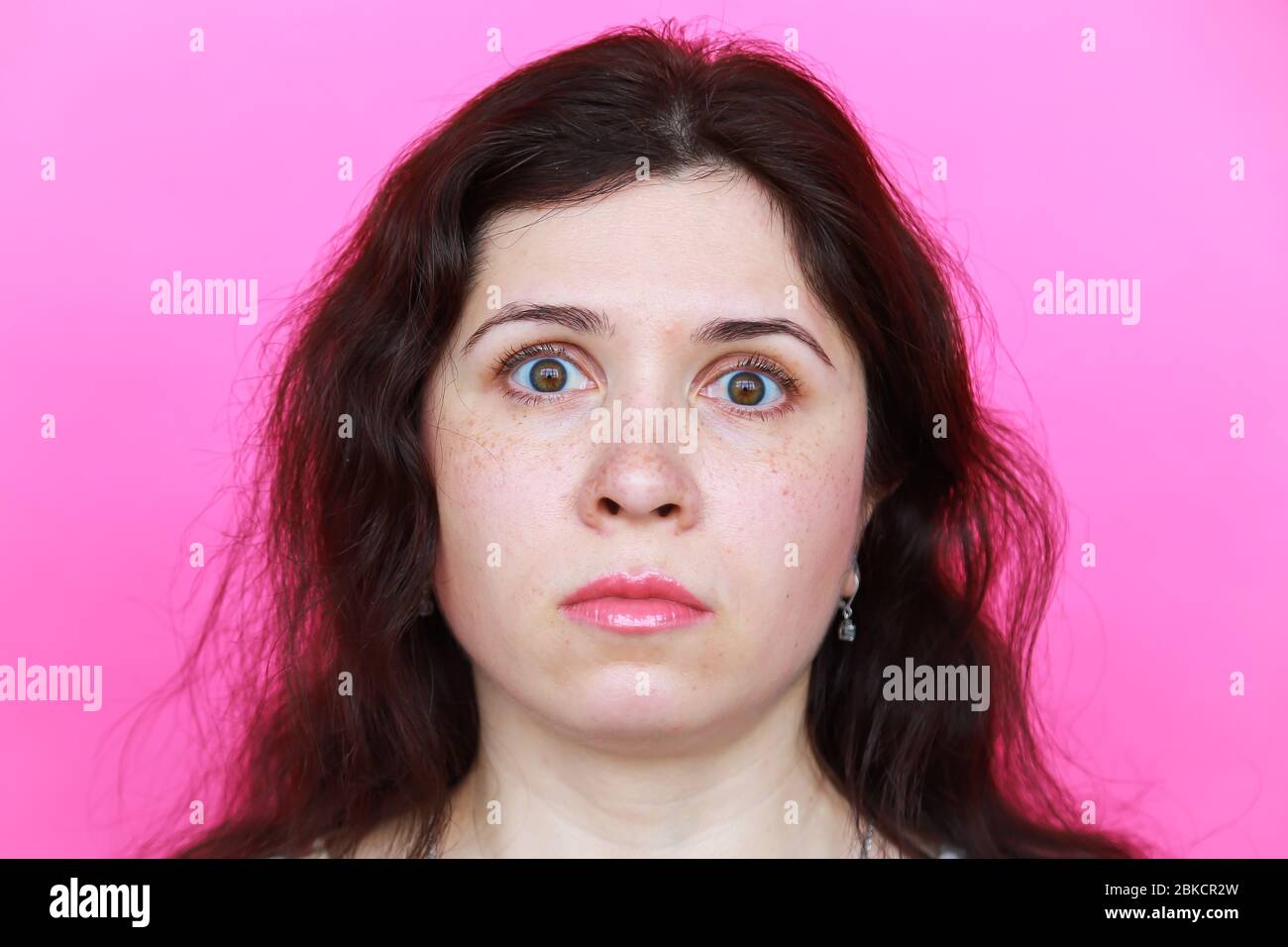 Surprised scared young woman on pink background Stock Photo - Alamy