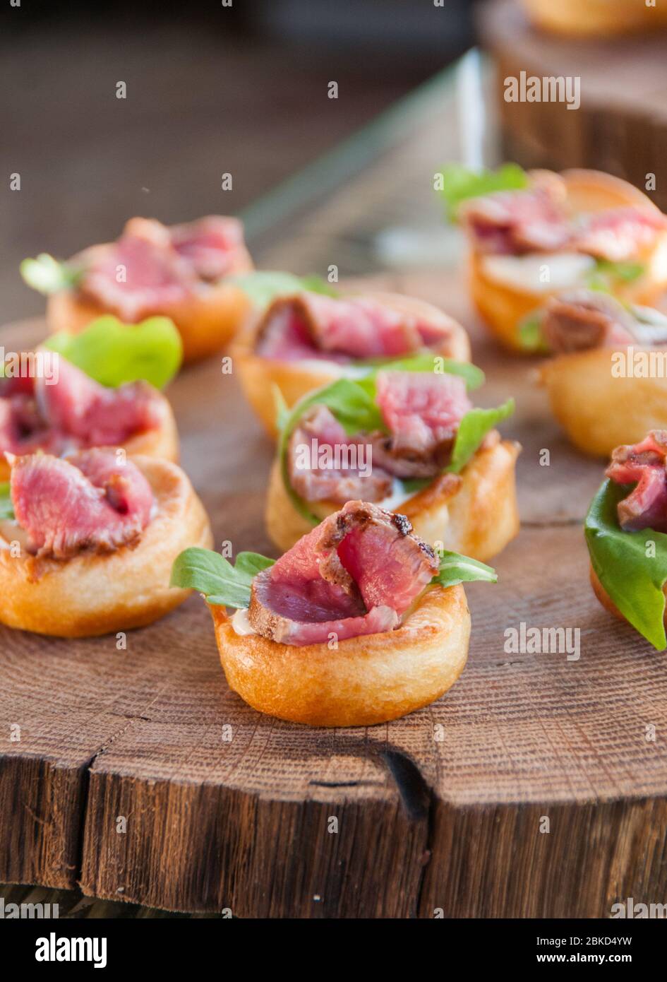 Bite-sized, mini yorkshire pudding with rare beef and basil on a wood ...