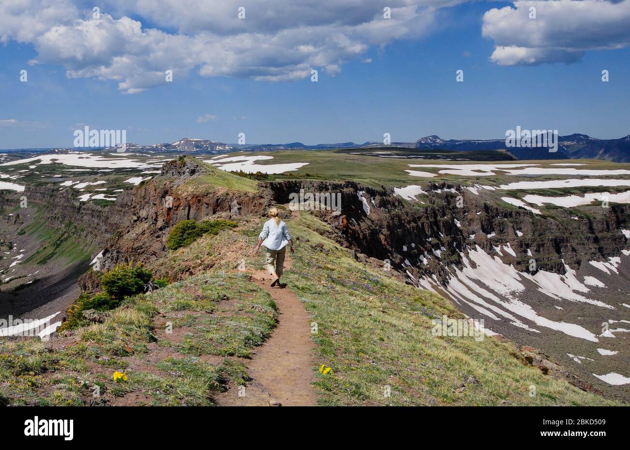 Woman hiker walking along a scenic trail with cliffs on either side ...
