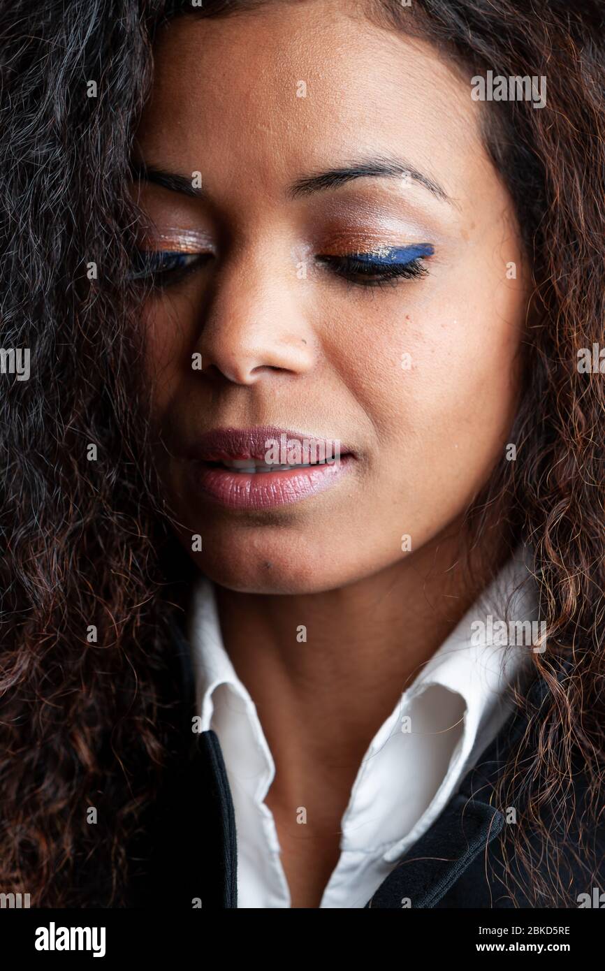 Attractive thoughtful woman wearing eye makeup looking down with parted ...