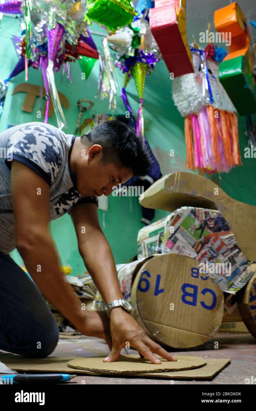 Craftsman making piñatas with newspaper and cardboard in his small ...