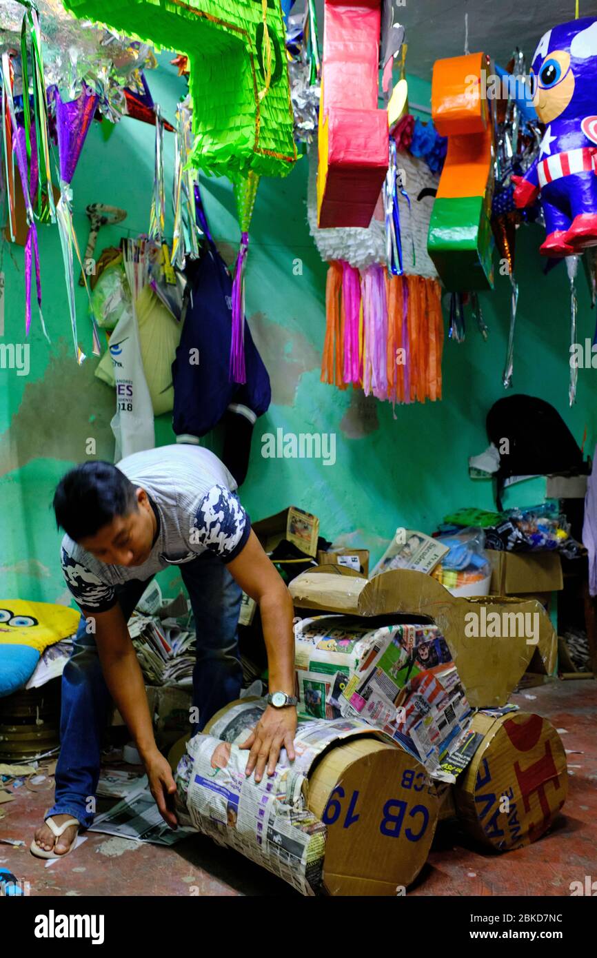 Craftsman making piñatas with newspaper and cardboard in his small ...
