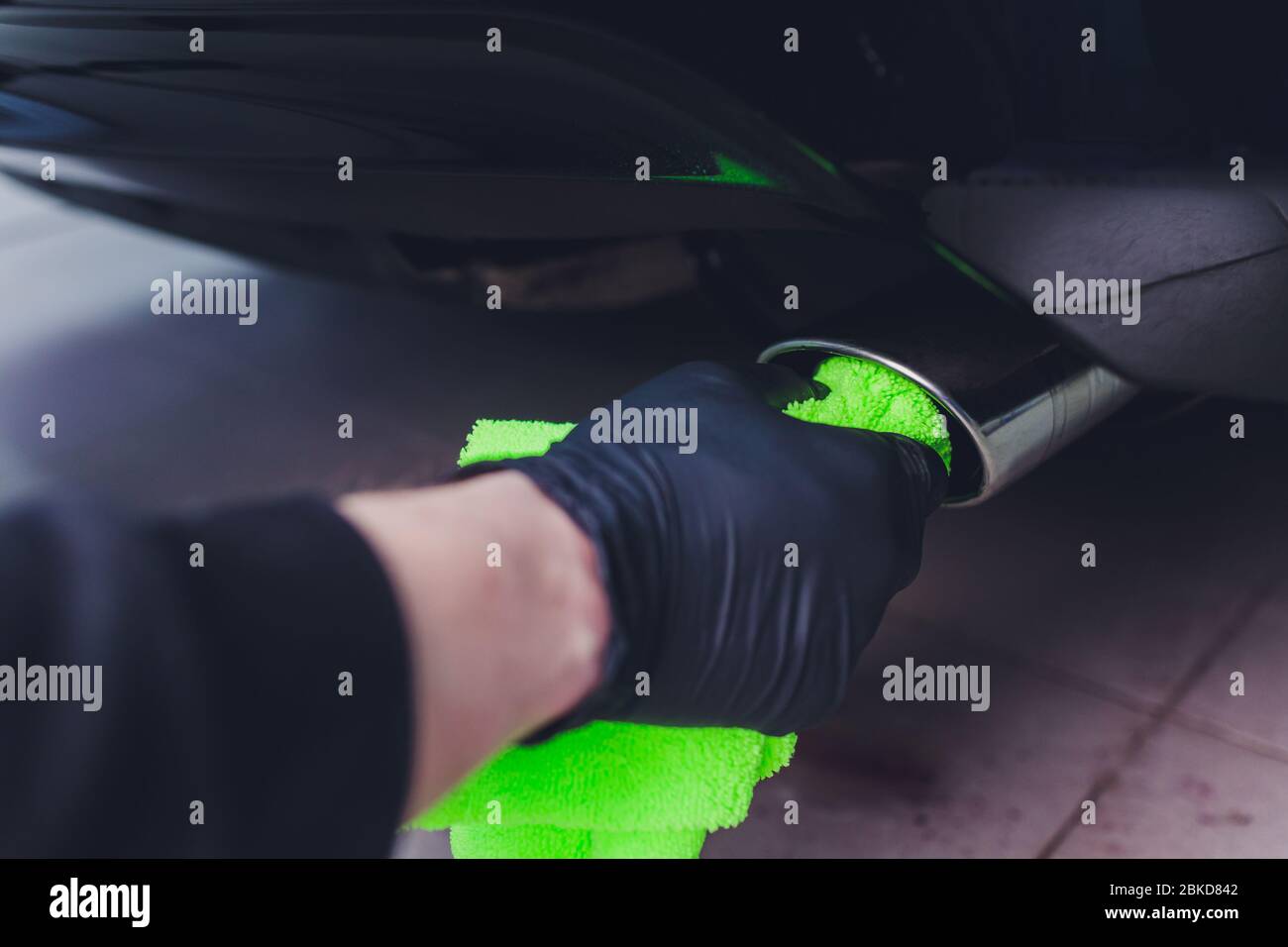 Car exhaust pipe with soap. Car wash background close-up of a green rag ...