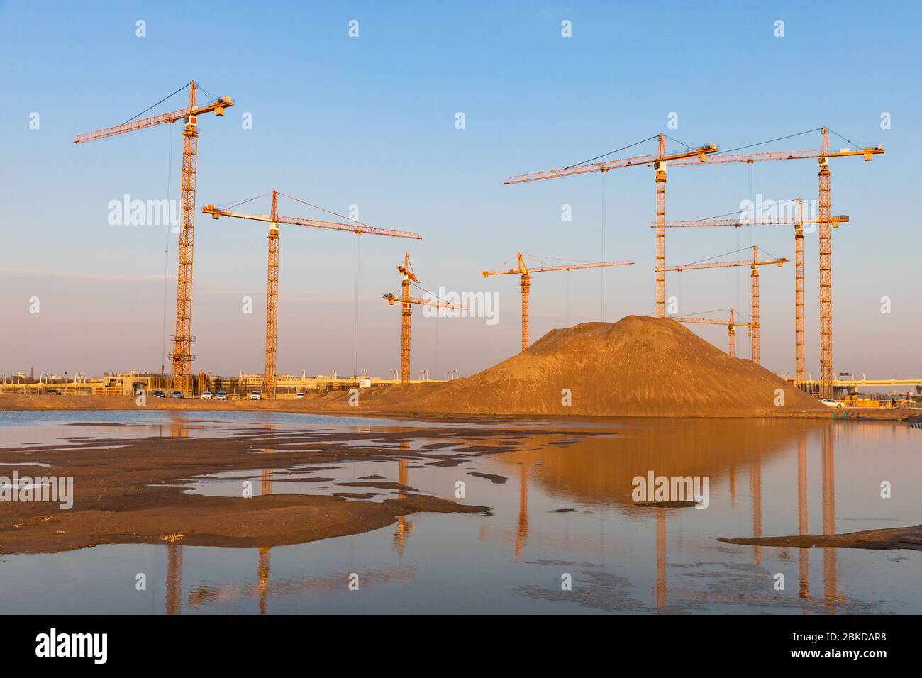 High pile of sand and group high-altitude tower cranes at construction ...