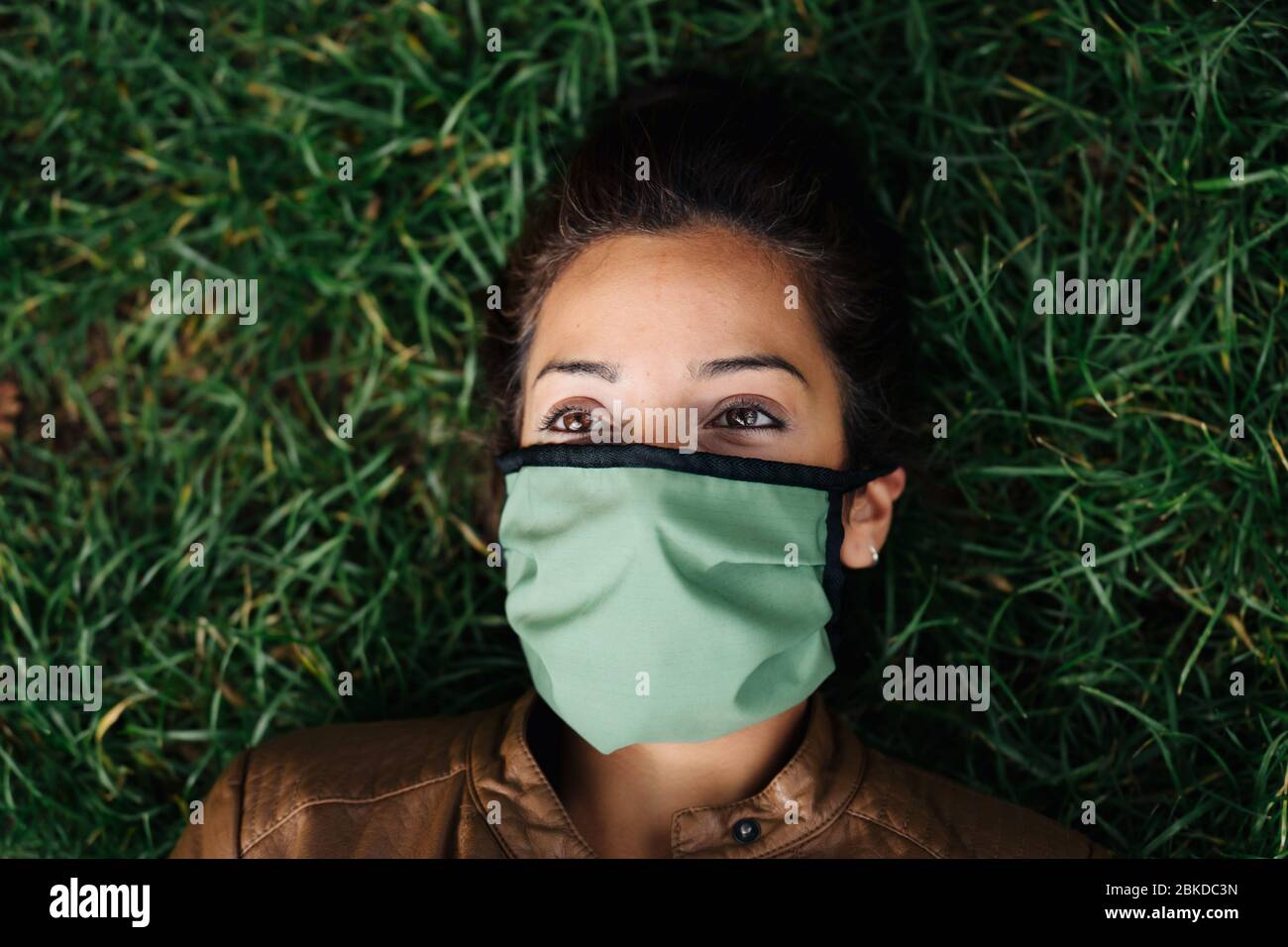 photo of a woman's face wearing a face mask lying in the grass Stock ...