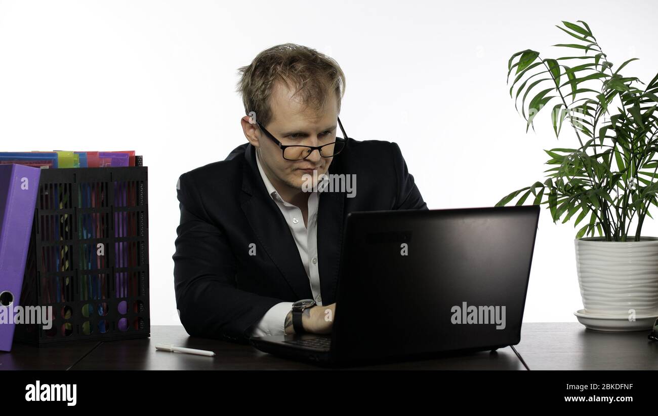 Tired disheveled clerk man working hard on laptop sitting at the office ...
