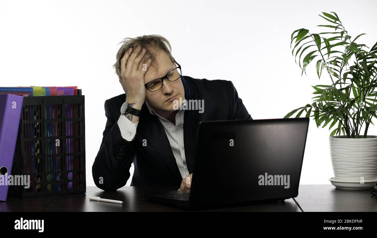 Tired sleepy disheveled clerk man working hard on laptop sitting at the ...