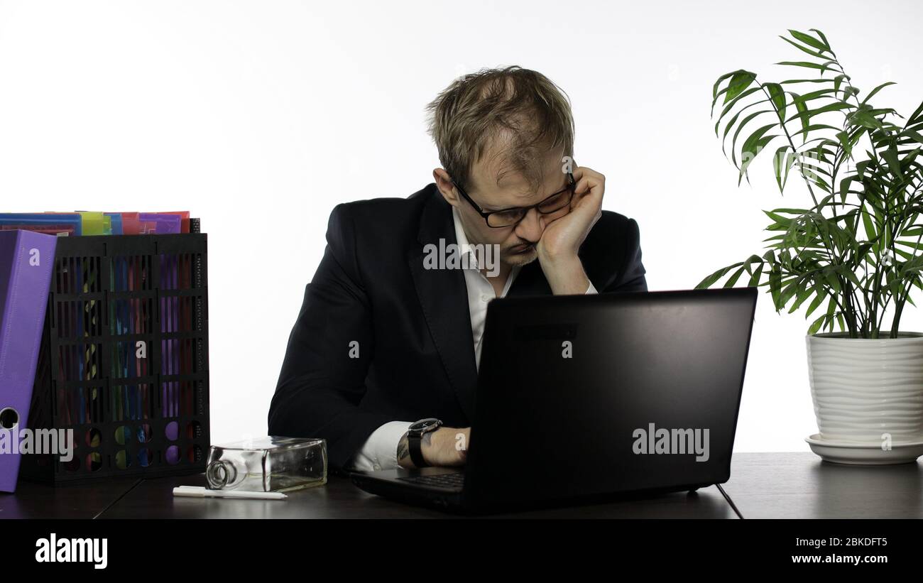 Tired disheveled clerk man working hard on laptop sitting at the office ...
