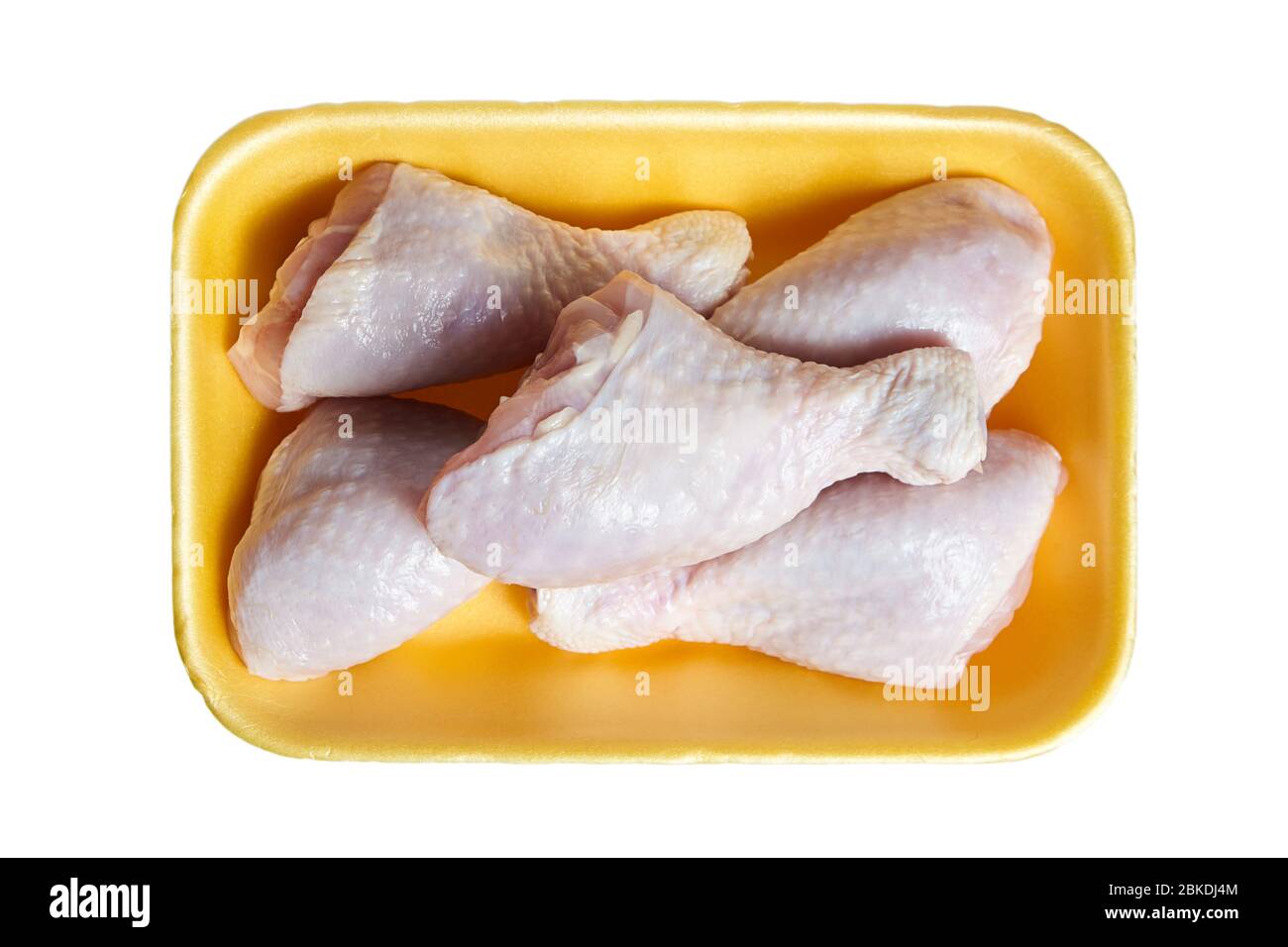 Raw and uncooked chicken legs with skin in a yellow plastic container ...