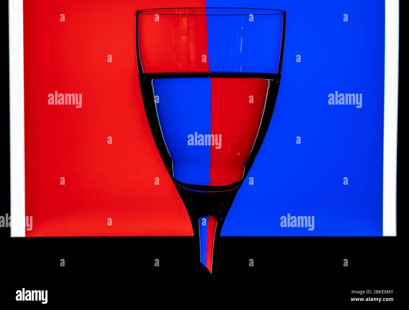 Glass of water against a two-color background. Water in refracting ...