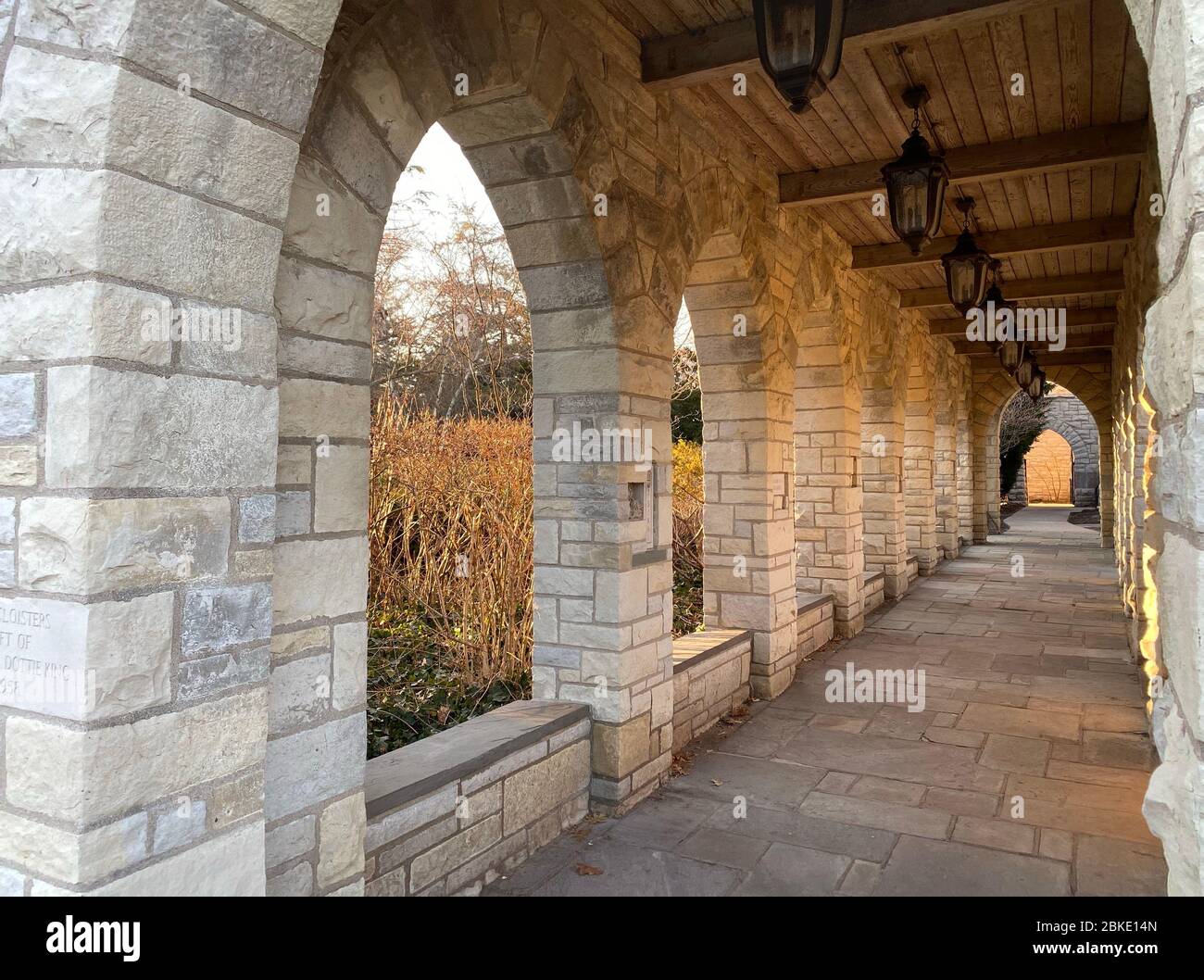 Cloistered stone archway in front of a church in the late afternoon sun ...
