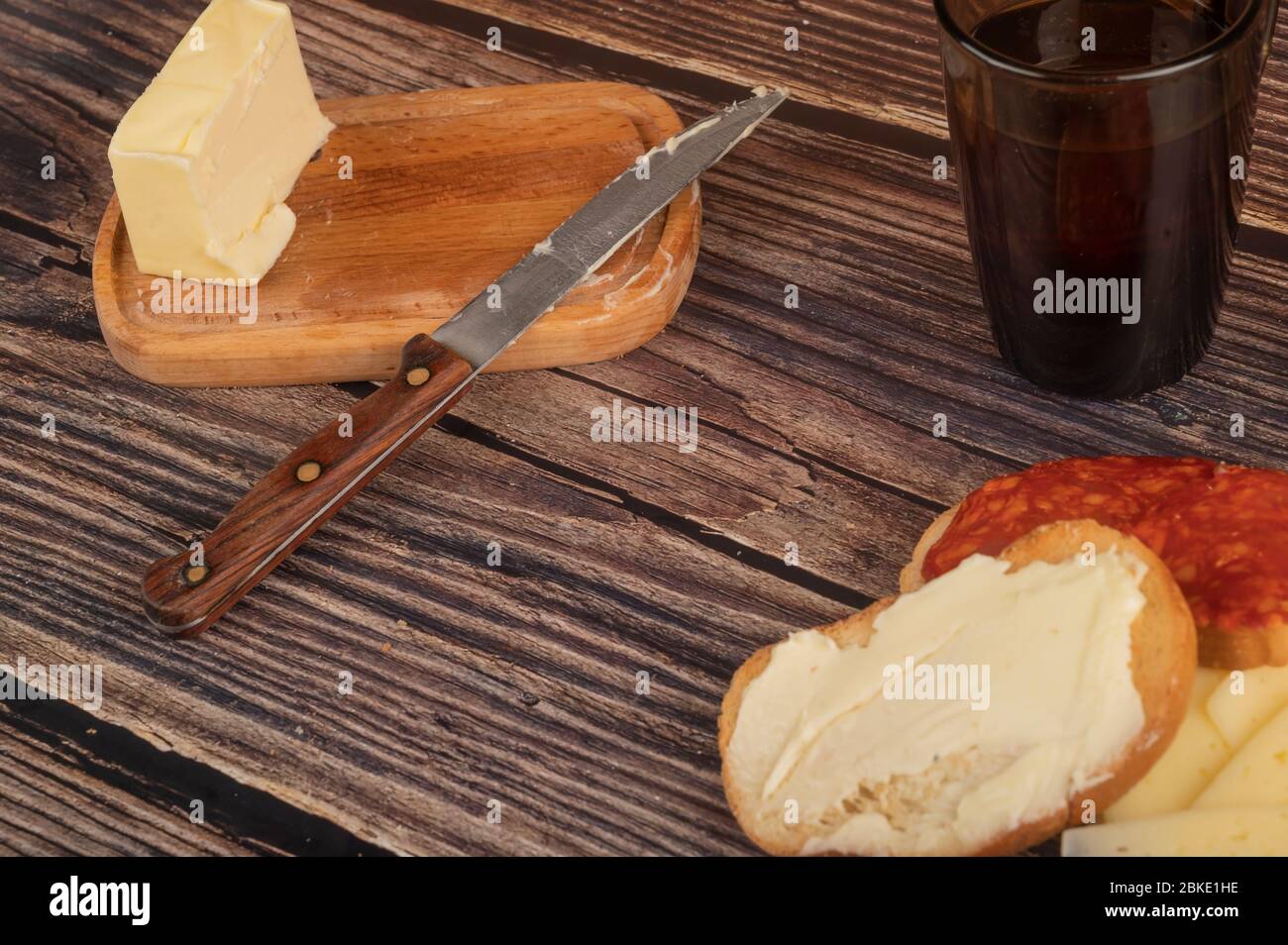 Fresh wheat toast with butter, sausage and cheese, a wooden butter dish ...