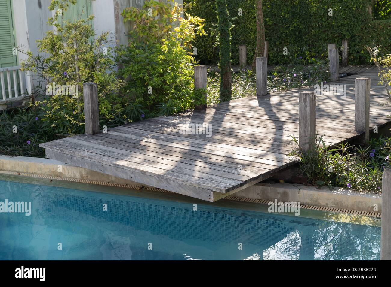 Wooden pathway on the swimming pool with green trees background Stock ...