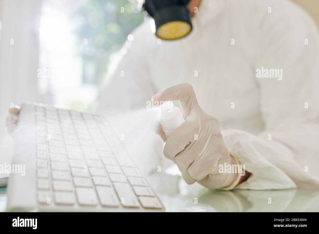 technician spraying frequently touched computer keyboard with cleaning ...