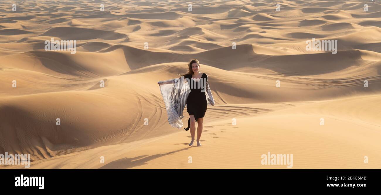 A girl in a black dress fell into a sandstorm among dunes and mountains ...