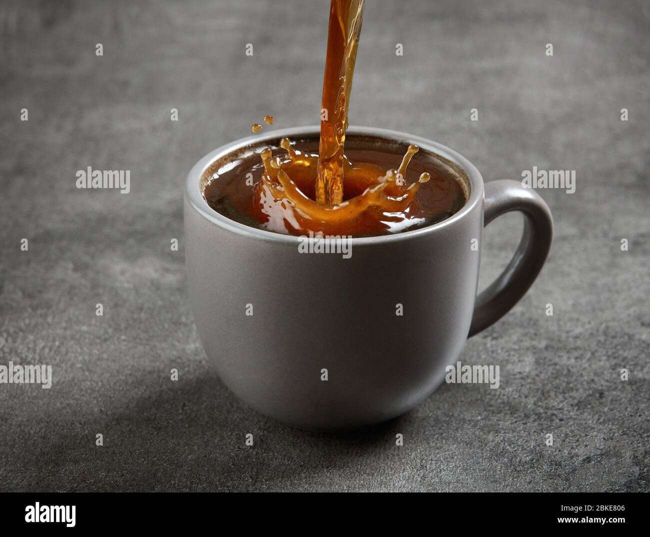 coffee pouring into cup on grey background Stock Photo - Alamy