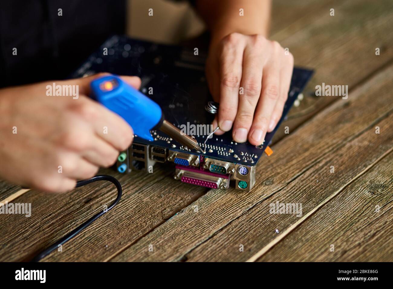 Technician or engineer is focused on repairing electronic circuit board with soldering iron. Man ...