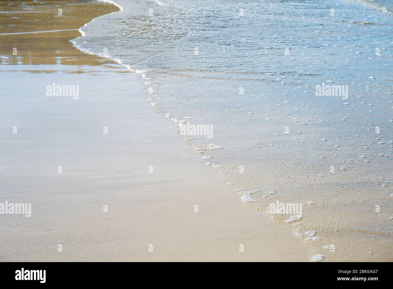Waves on sand beach with background at sunlight Stock Photo - Alamy