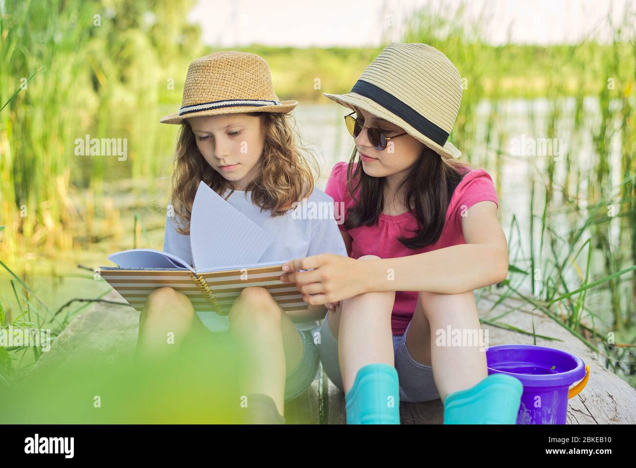 Children two girls resting playing reading their notebook in nature ...