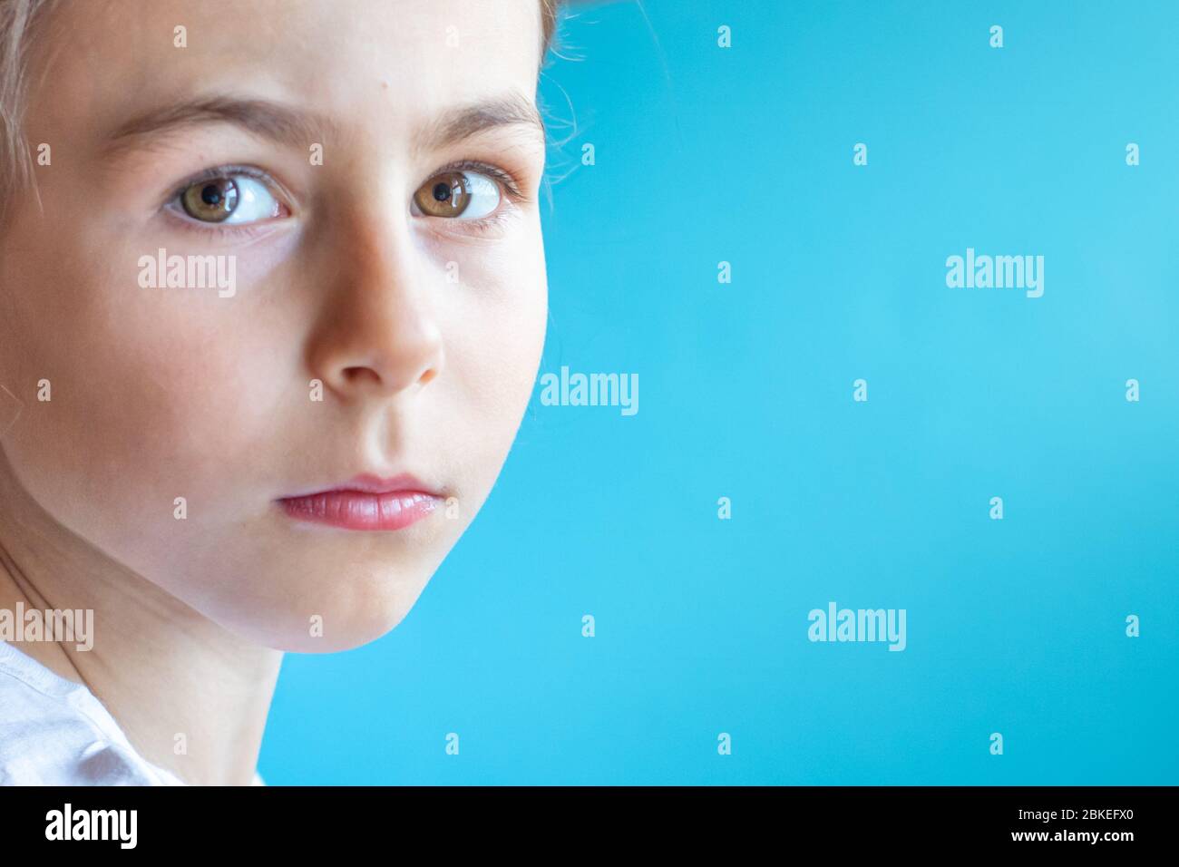 Portrait of a child girl with a worried face close-up on a blue ...
