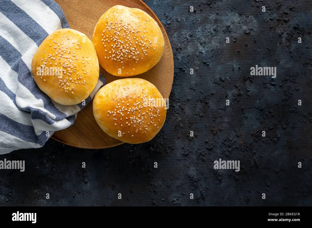 Three isolated fresh homemade burger breads on a dark blue background ...