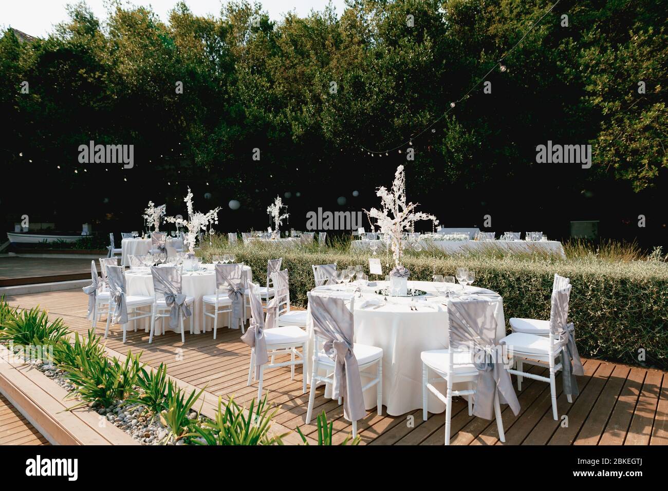Round tables with a white fabric tablecloth, white Chiavari chairs with ...