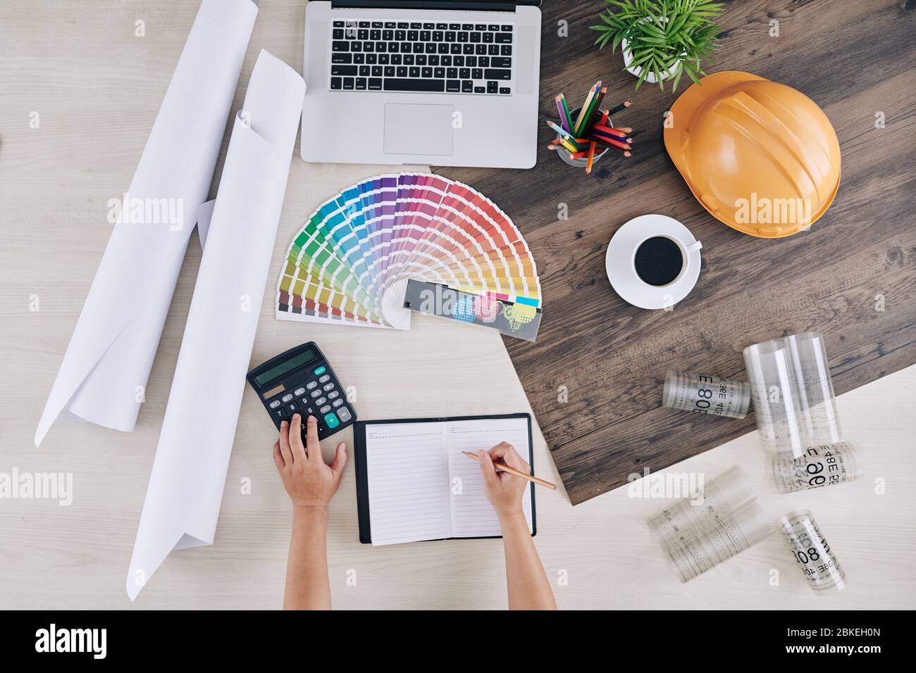 Interior designer writing ideas in planner and making calculations when ...