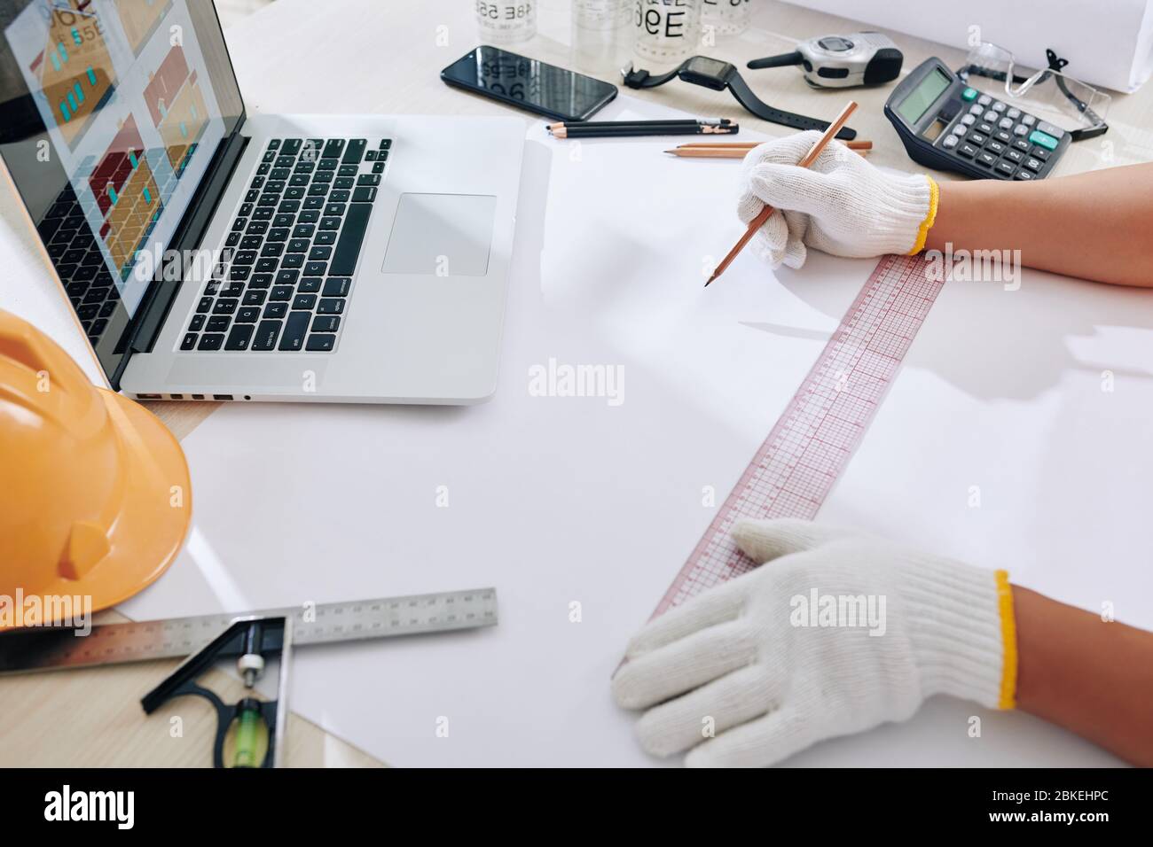 Engineer in textile gloves drawing plan of building with ruler and ...