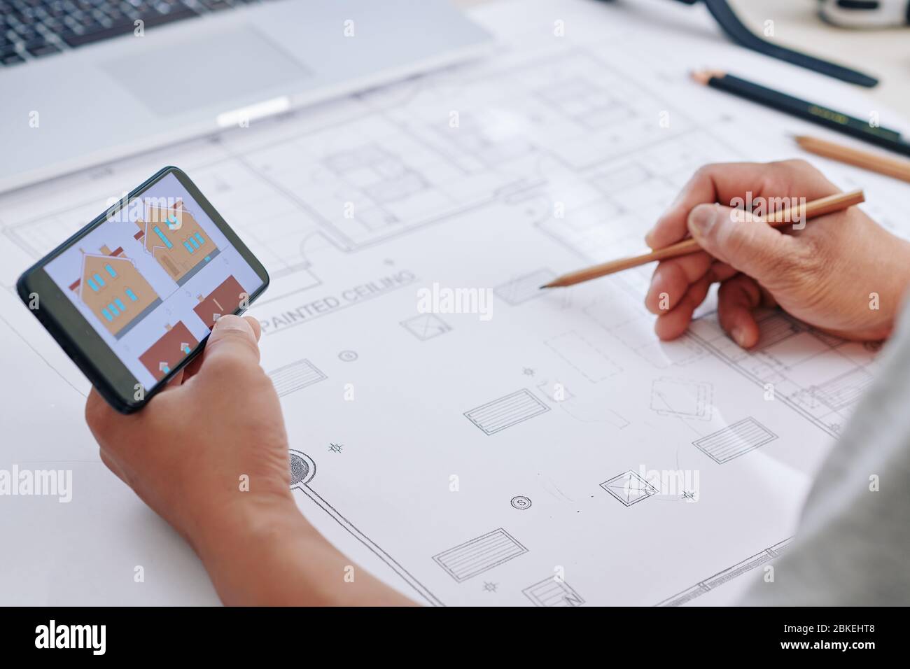 Construction engineer looking at drawing of house on smartphone screen ...