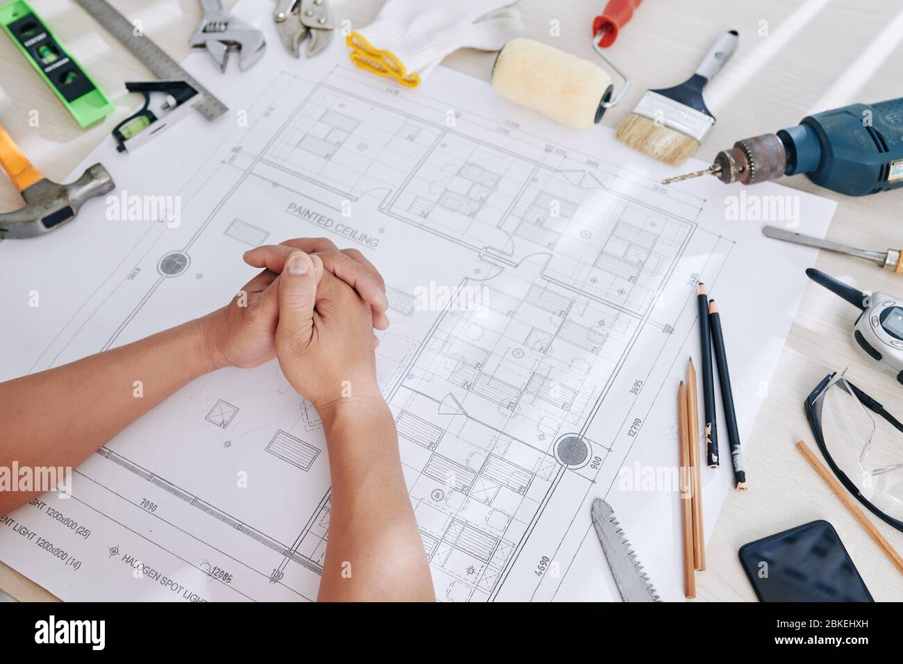Construction engineer sitting at desk with working tools and blueprint ...