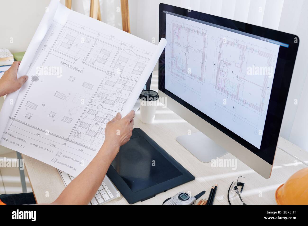 Architetect opening construction blueprint and comparing it with house ...
