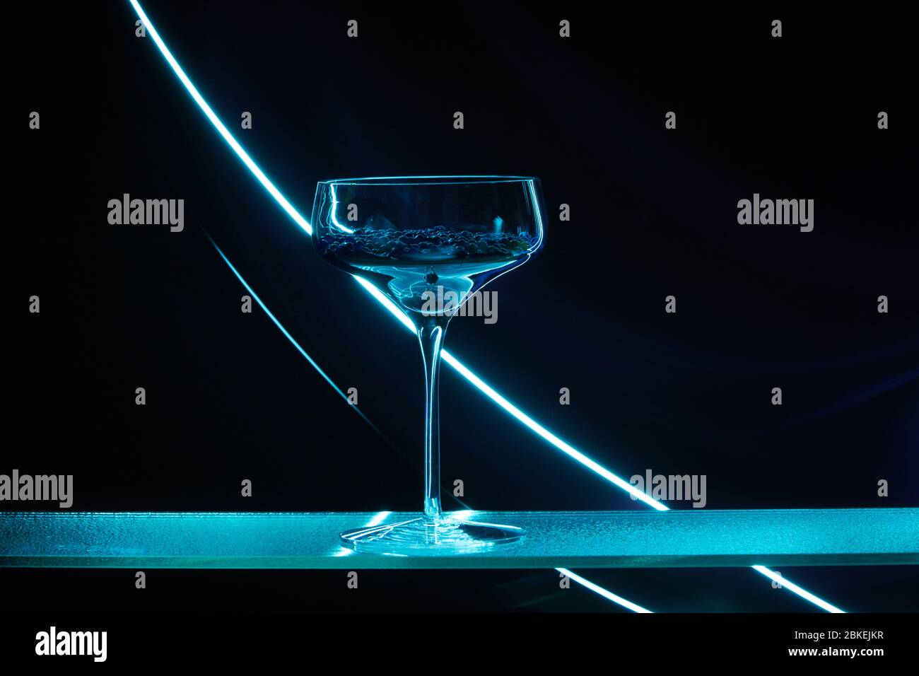 Single martini style cocktail glass illuminated display with blue ...