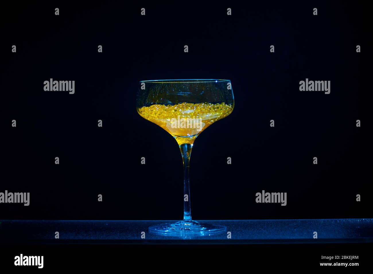 Single martini glass illuminated display, yellow coloured water caviar ...